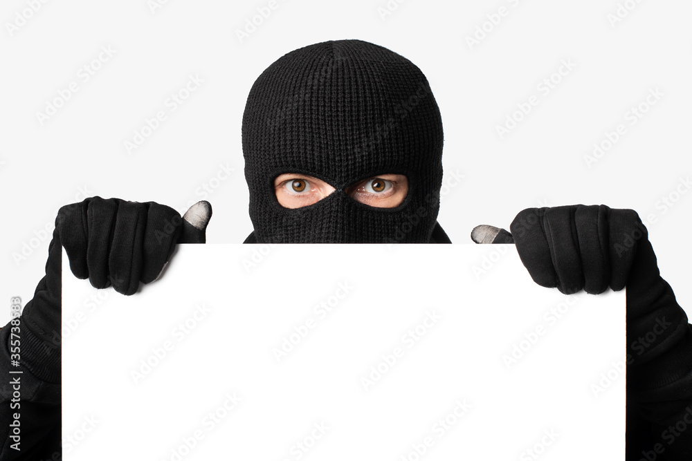 Masked thief peeking out white blank board Stock Photo | Adobe Stock