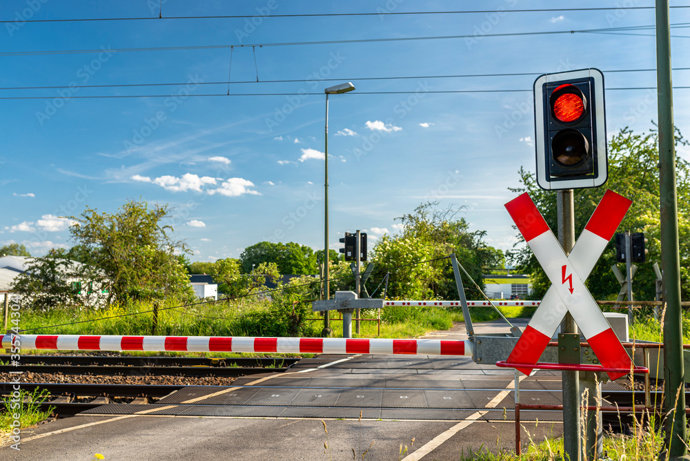 Guarded railroad crossing with closed barriers, red warning light and ...