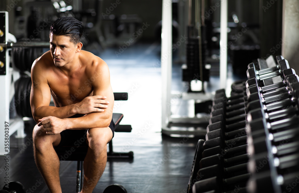 sportsman taking a break after training at the gym sitting and drinking ...