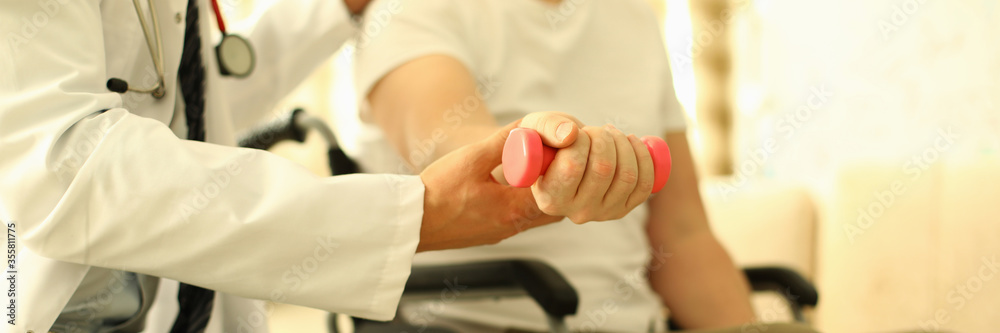 Handicapped man sits working out dumbbell arm. Rehabilitation after ...