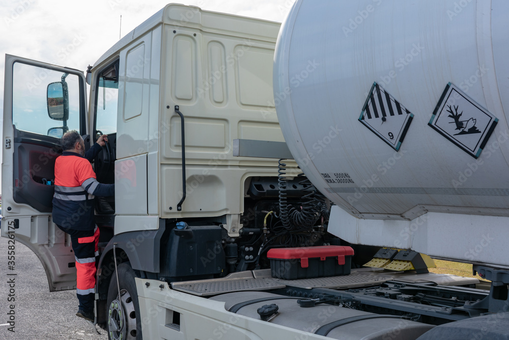 Dangerous goods tank truck driver getting into the cab using the two ...