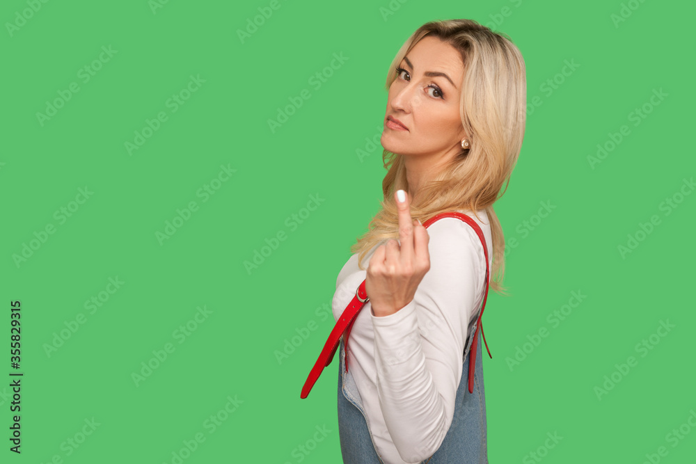 Portrait of impolite rude adult woman in denim overalls rejecting ...