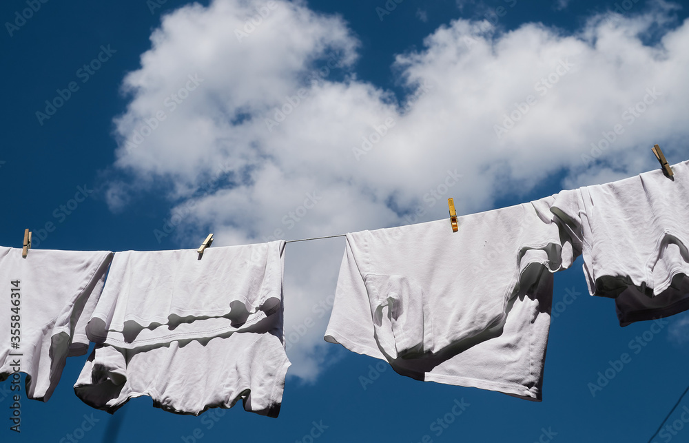white clothes dried on a rope against a blue sky. White clothes drying ...