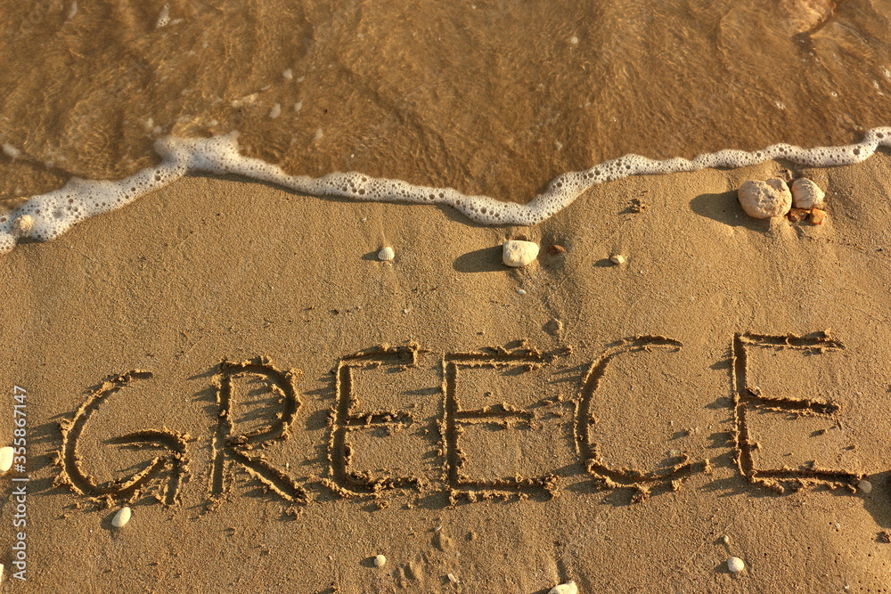 Greece Hand Written on Sandy Texture at a Sunny Beach with Pebbles and ...