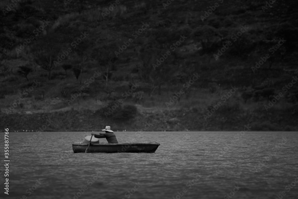 Lancha con lanchero remando cerca de la costa de un lago con una ...