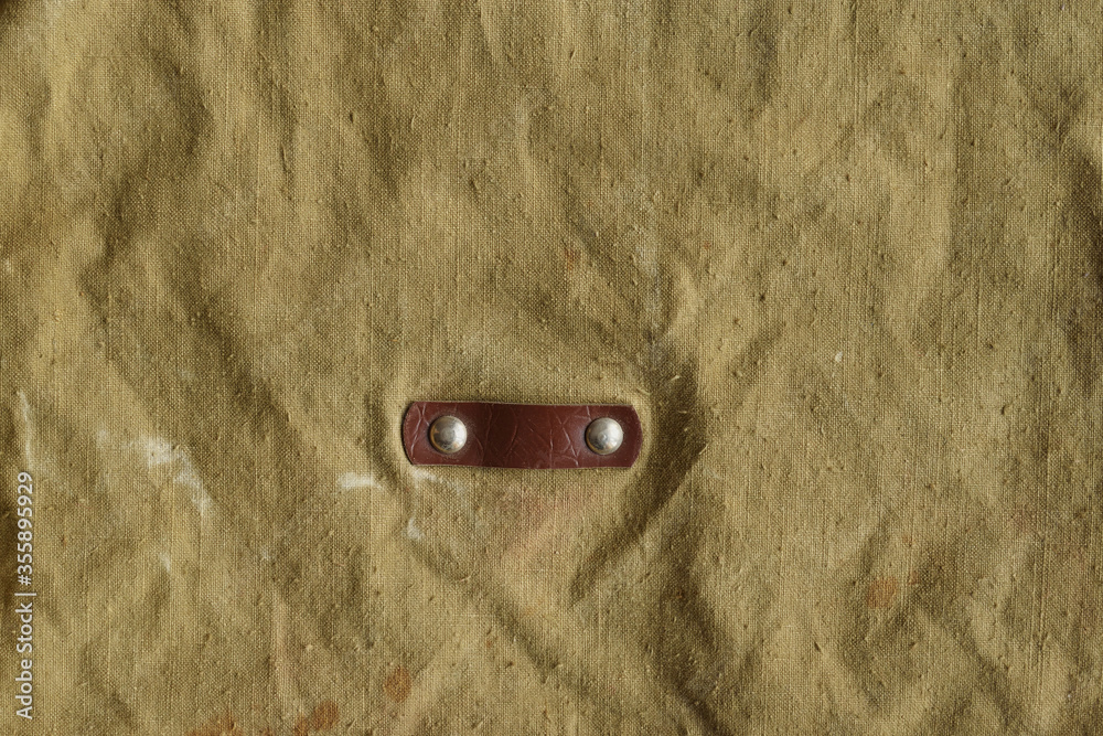 Crumpled dirty khaki color tarpaulin with a brown leather tab, detailed ...