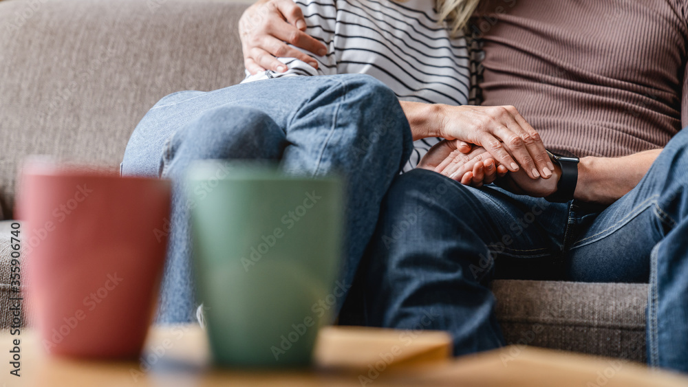 Cropped image of couple holding hands each other and hugging at home ...