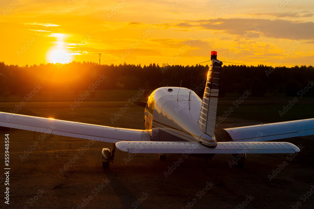 Rear view of a parked small plane on a sunset background. A silhouette ...