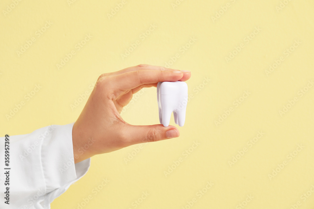 Hand of dentist with tooth on color background Stock Photo | Adobe Stock