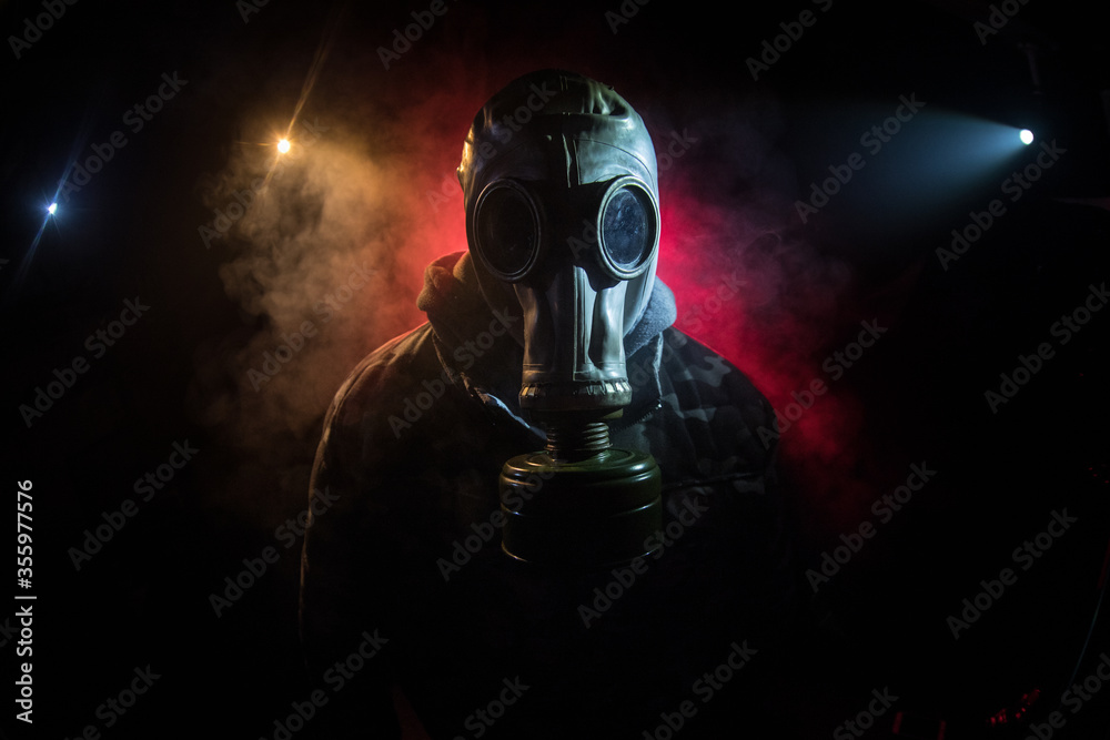 Gas mask with clouds of smoke on a dark background. Sign of radioactive ...