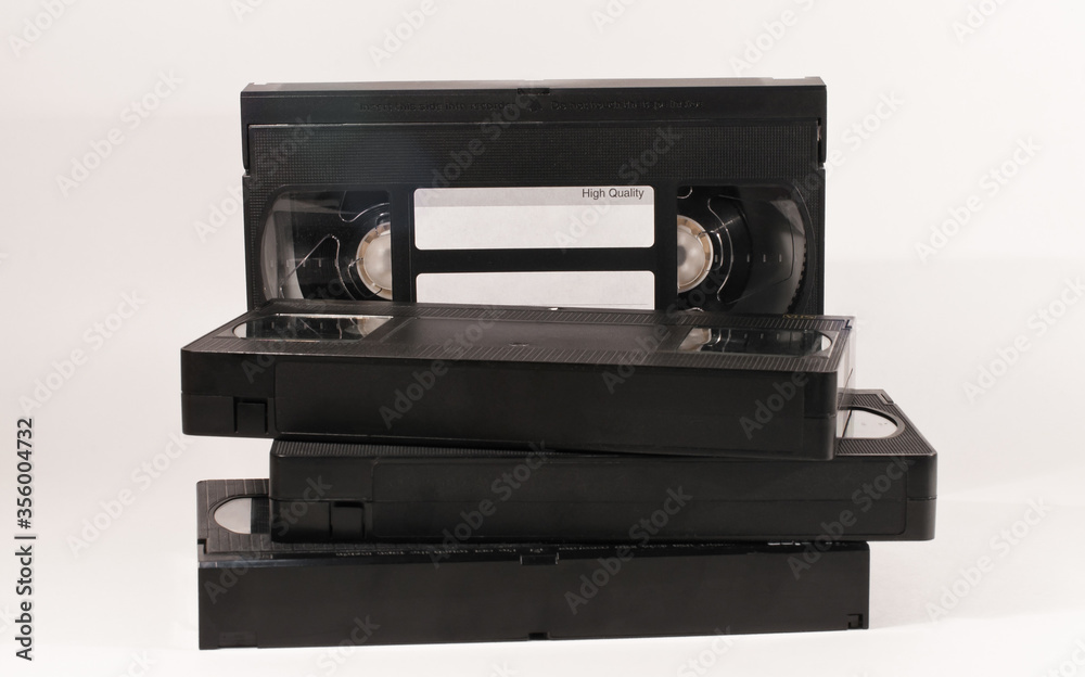 a stack of black vhs video cassettes on a pure white background. old ...