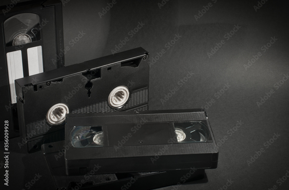 a stack of black vhs video cassettes on a black background. old film ...