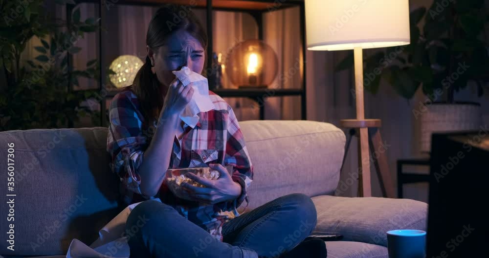 Sad woman crying and eating popcorn while watching movie at night Stock ...