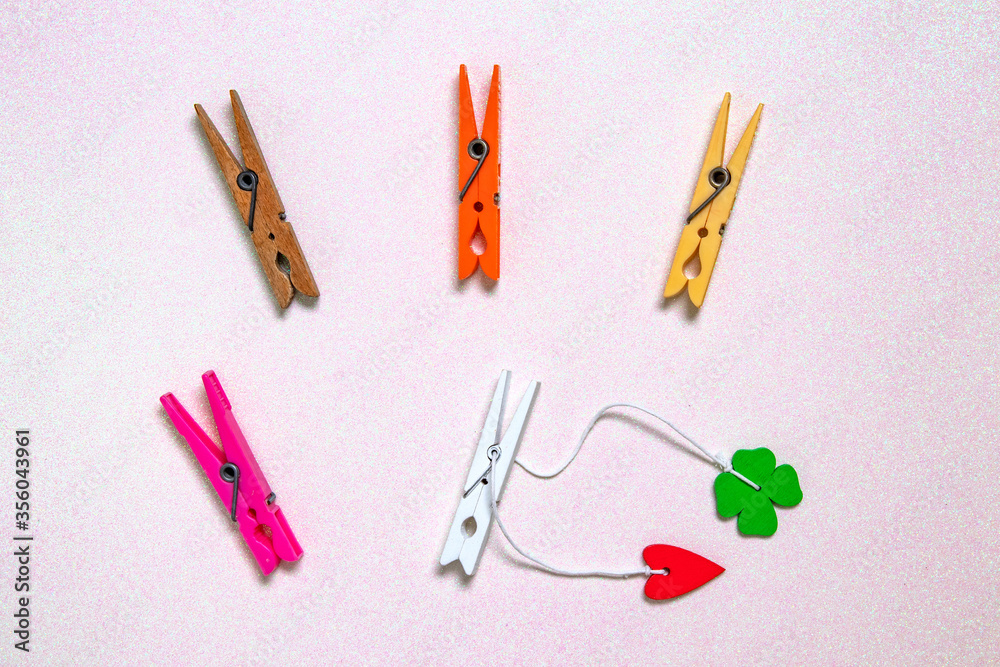 Colorful set of five wooden and plastic clothespins on a light pink ...