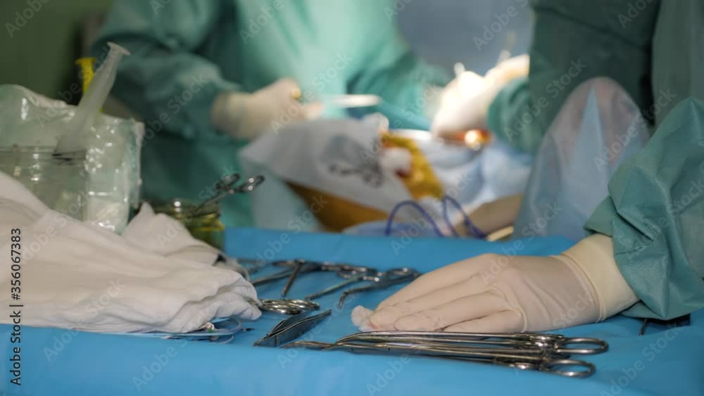 Nurse assisting doctors surgeons during surgical procedure in operating ...