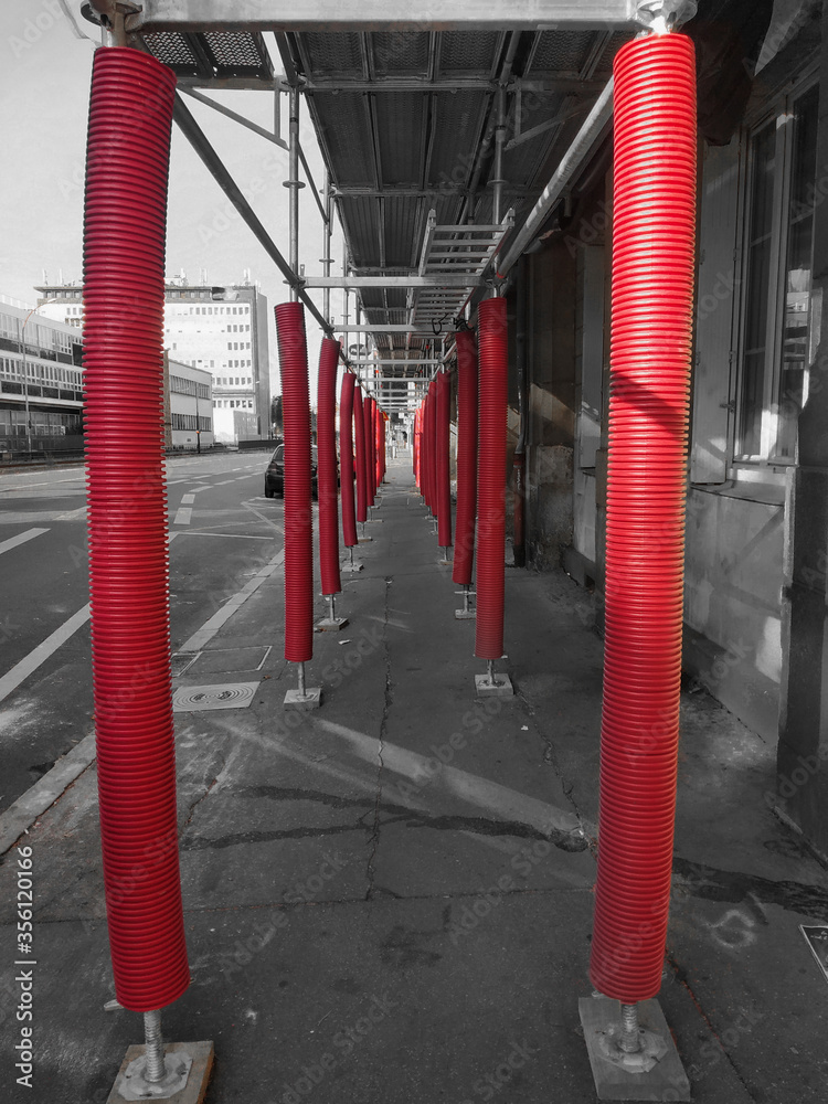 Red pillars creating a perspective path from corrugated plastic tubes ...