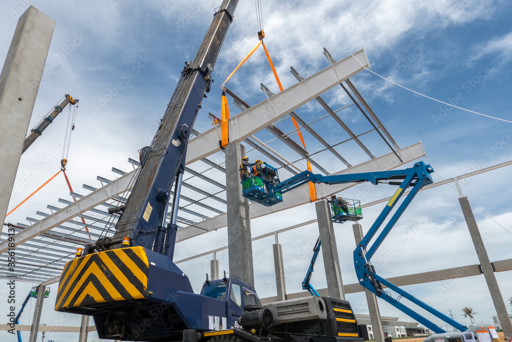 Construction worker working at boom lift installation steel roof beam ...