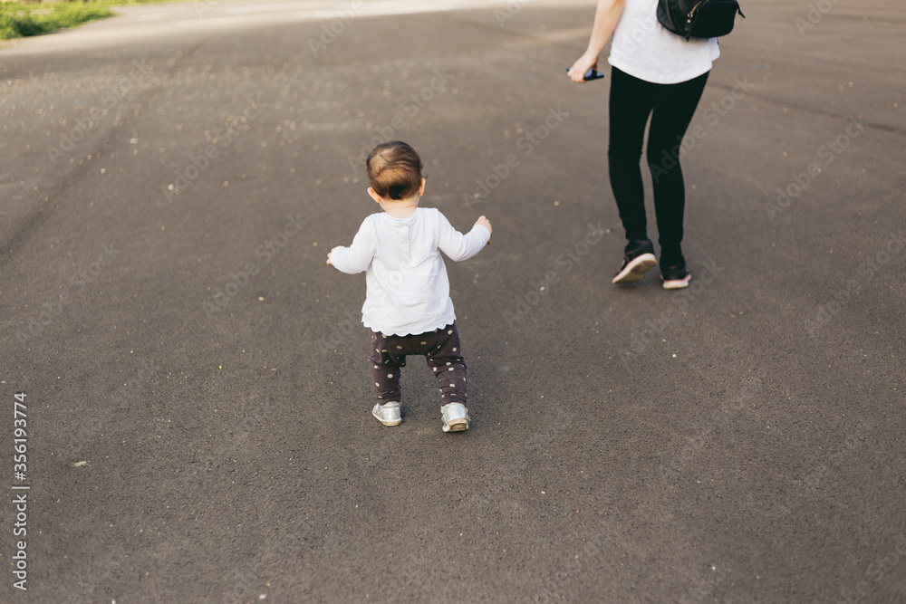 First steps of little girl. Mother and her toddler on playground. Baby ...