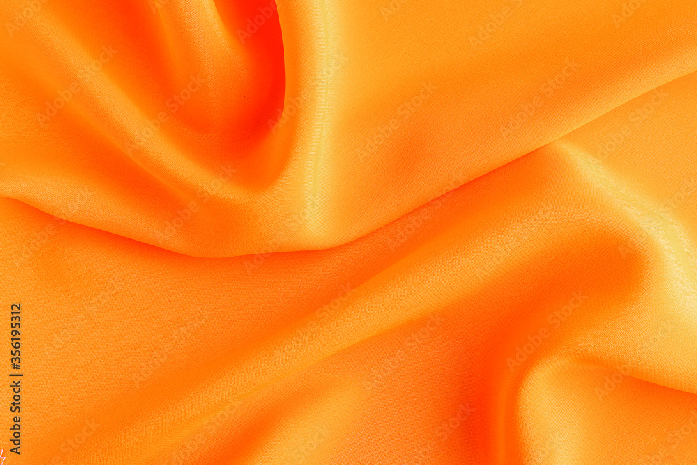 Satin silk fabric orange color for the background. Crumpled wavy silk ...