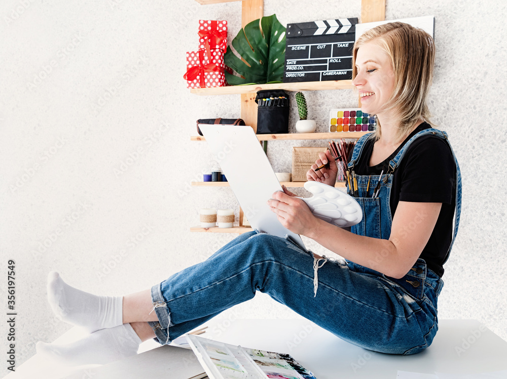 Laughing female artist drawing at home sitting on her desk Stock Photo ...