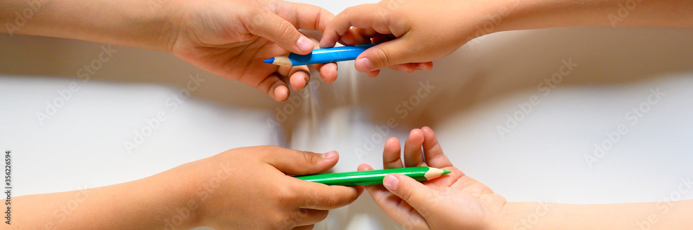 kid's hands share each other colored pencils on a white background ...