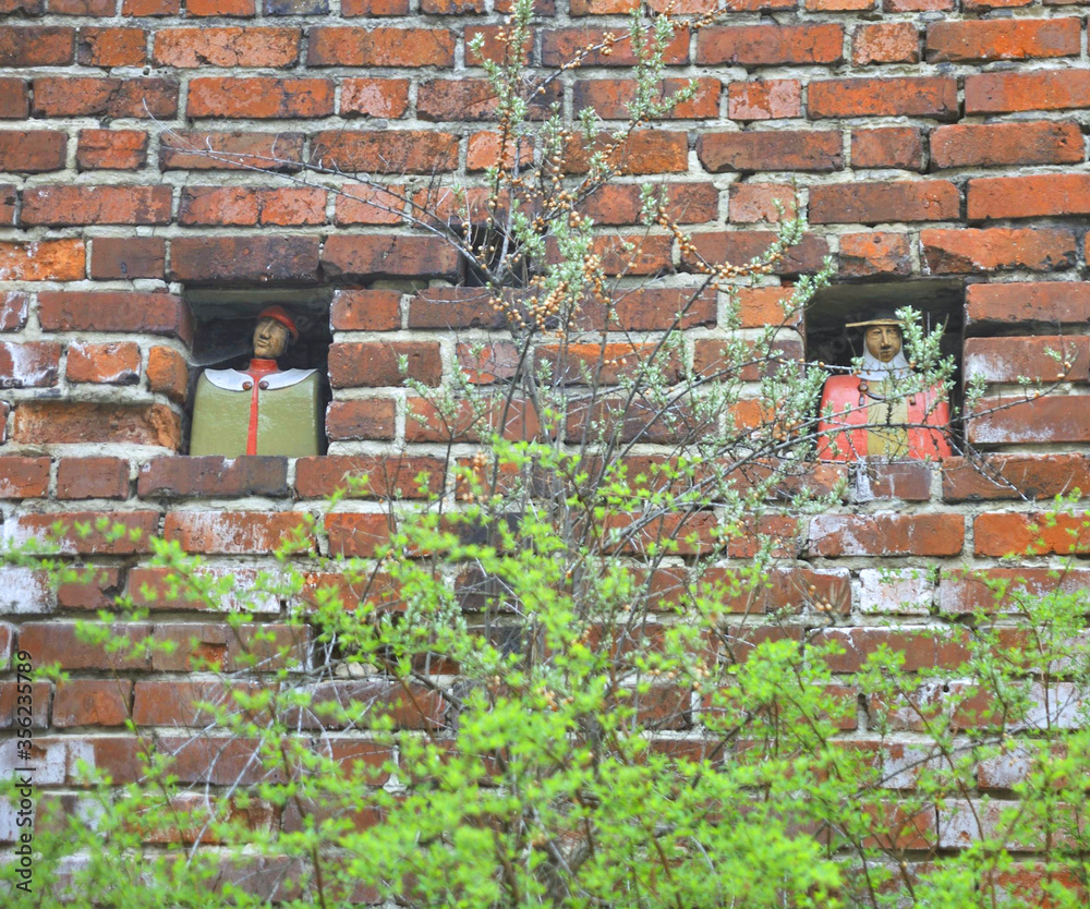 Foto de Small sculptures of two people looking from windows in brick ...