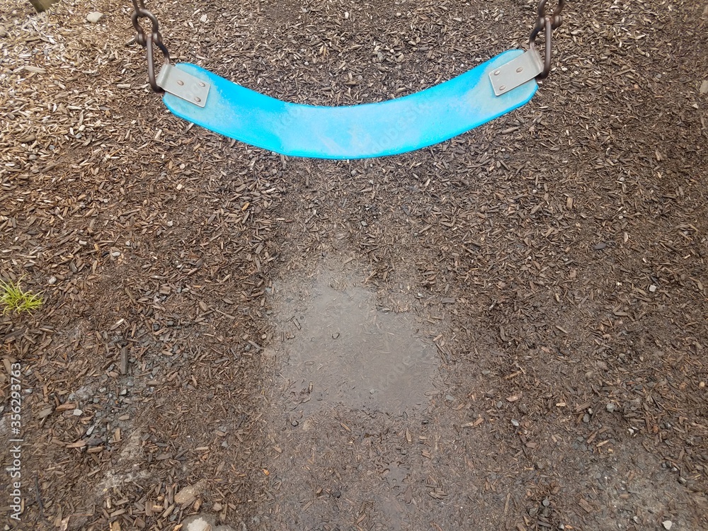 blue swing on playground with water puddle and wood chips Stock Photo ...