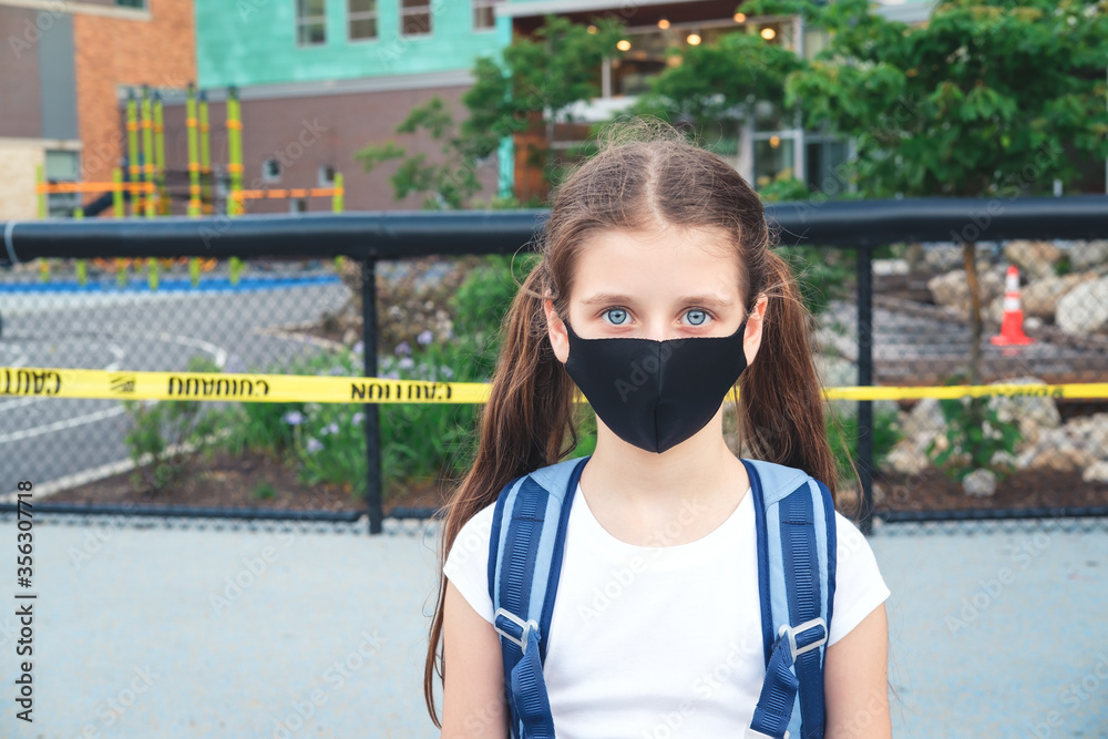 Elementary school student in a cloth dust mask with backpack near ...