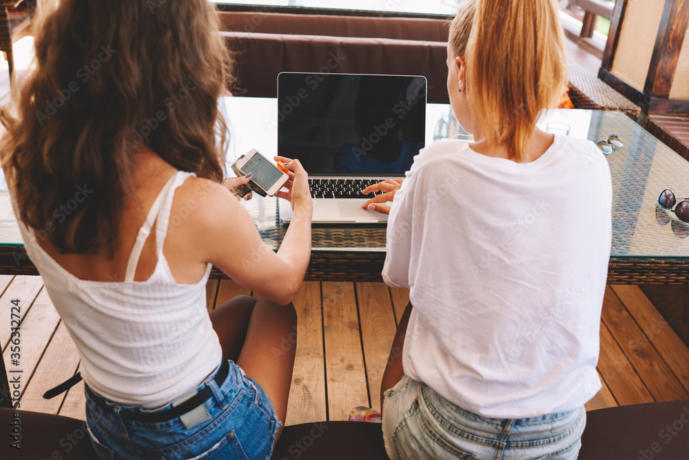 stylish hipster girls using cell telephone and net-book during morning ...
