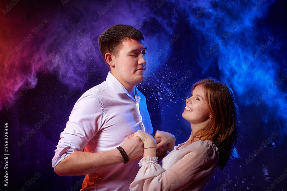 Beautiful young couple during a photo shoot with flour in a dark Studio ...