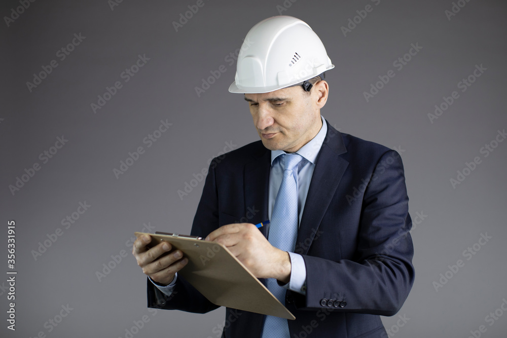 Handsome middle aged chief engineer in hard hat makes notes on ...