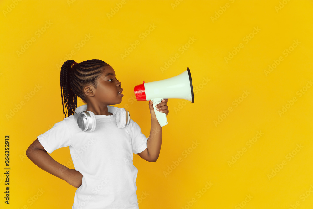 Shouting with megaphone, listen to music. Little african-american girl ...