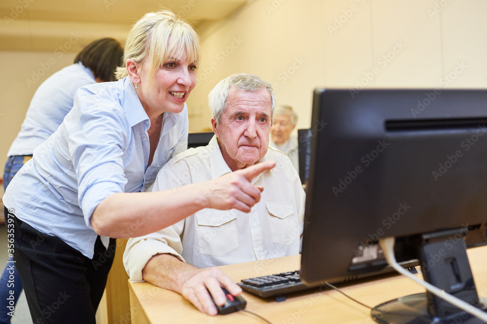 Teacher explains work on a PC to a senior Stock Photo | Adobe Stock