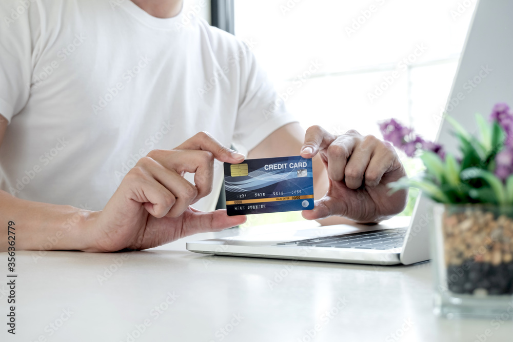 Young man people who hold credit cards and use laptops for online ...