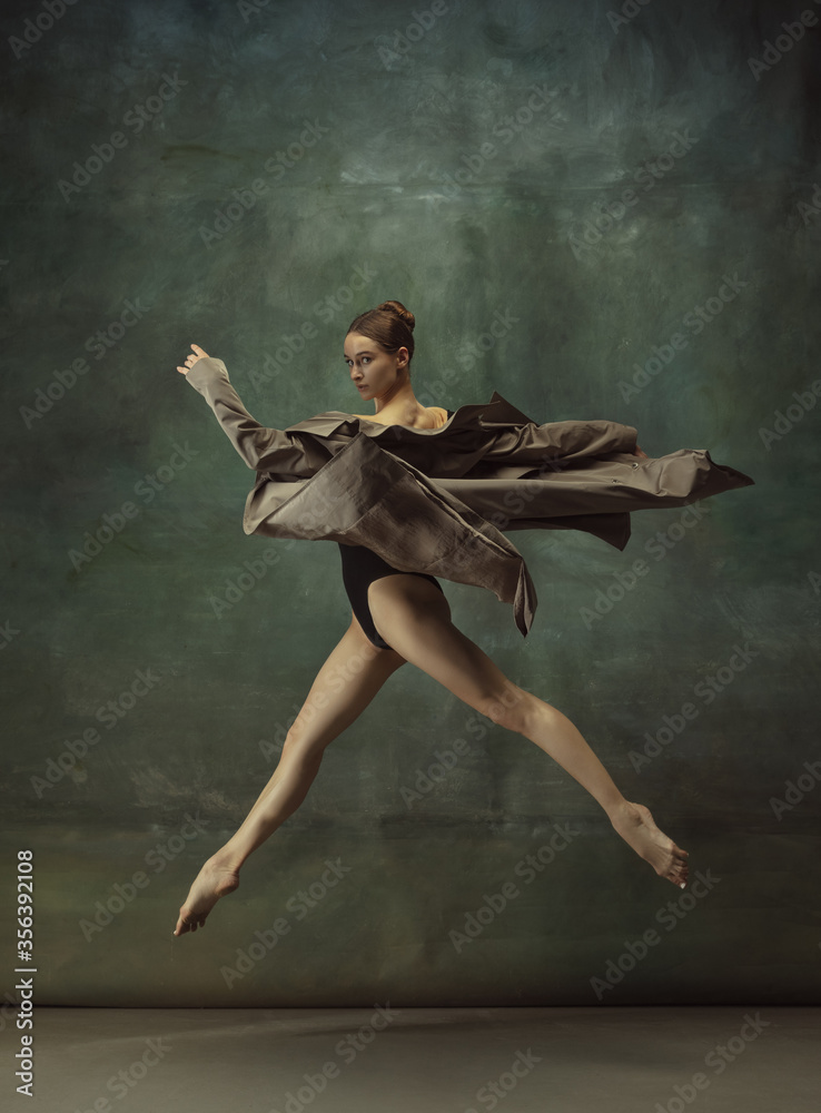 In flight. Graceful classic ballerina dancing, posing isolated on dark ...