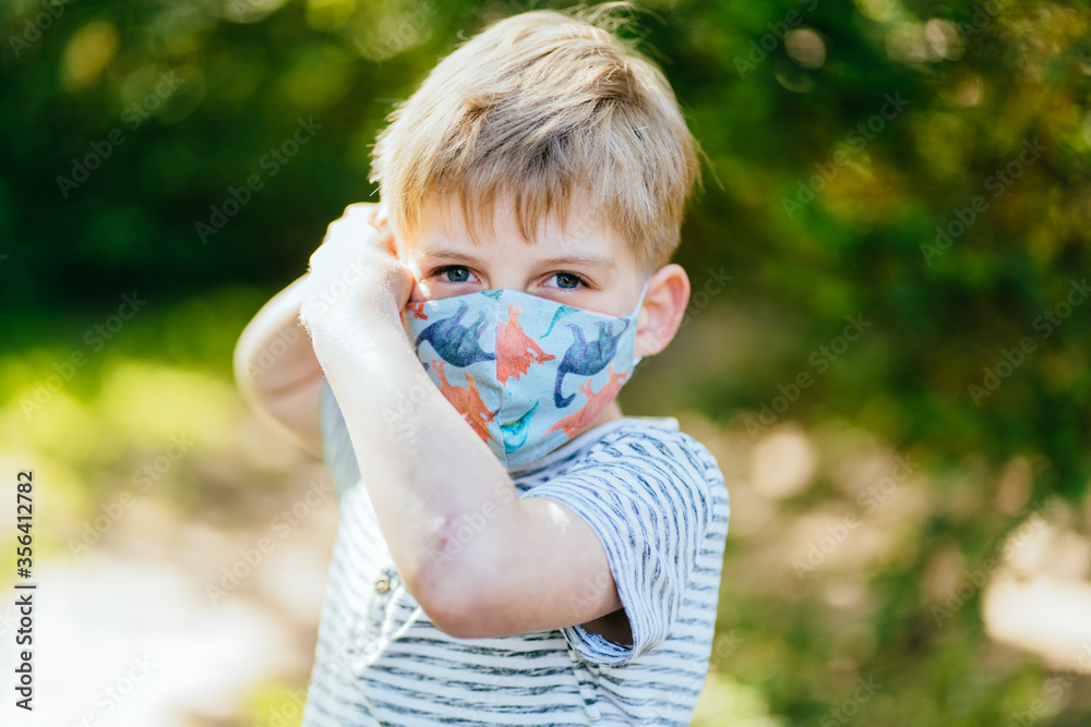 Blond kid boy children putting on protective mask correctly covering ...