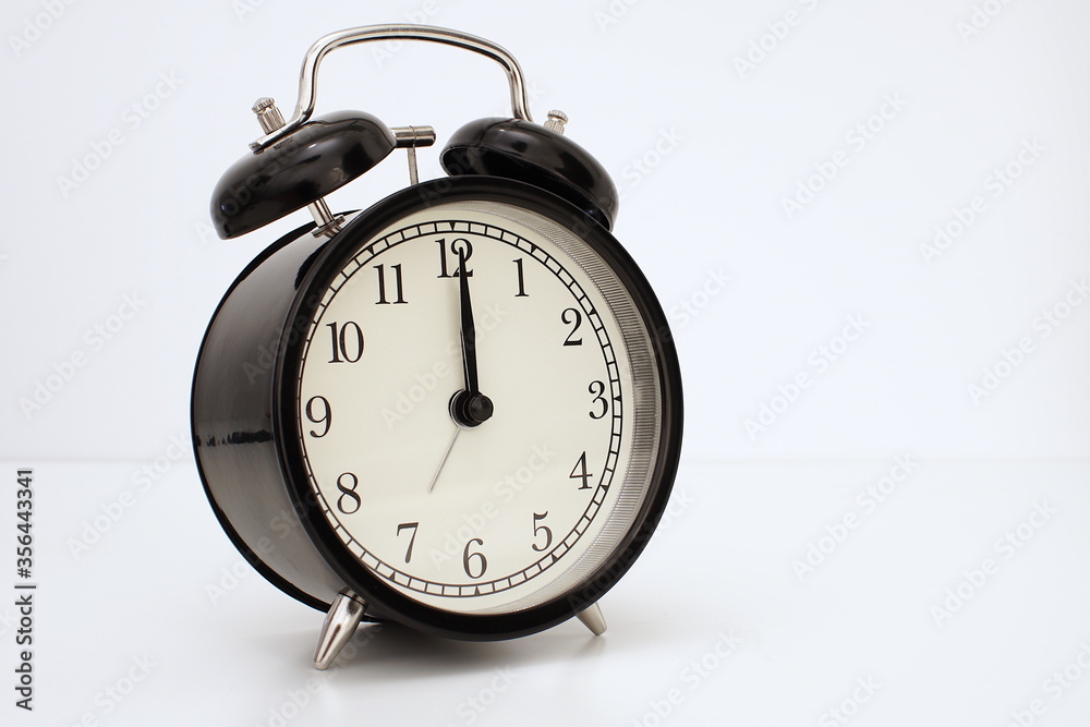 Black vintage alarm clock on table. White background. Wake up concept ...
