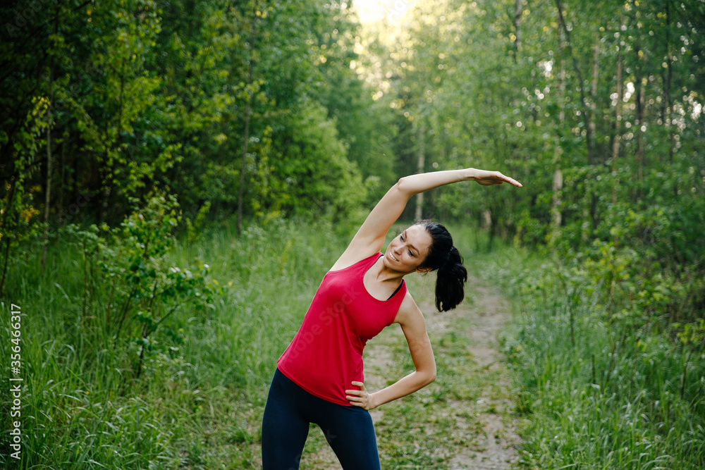 Fun girl exercising outdoors in green forest, activity with stretch ...