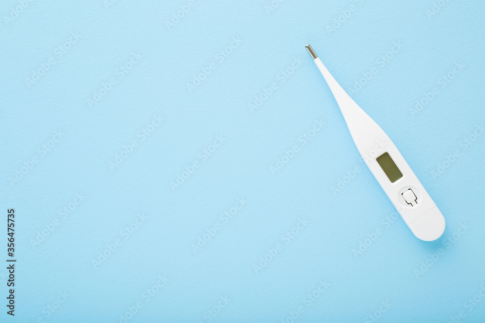 White digital thermometer on light blue table background. Pastel color ...