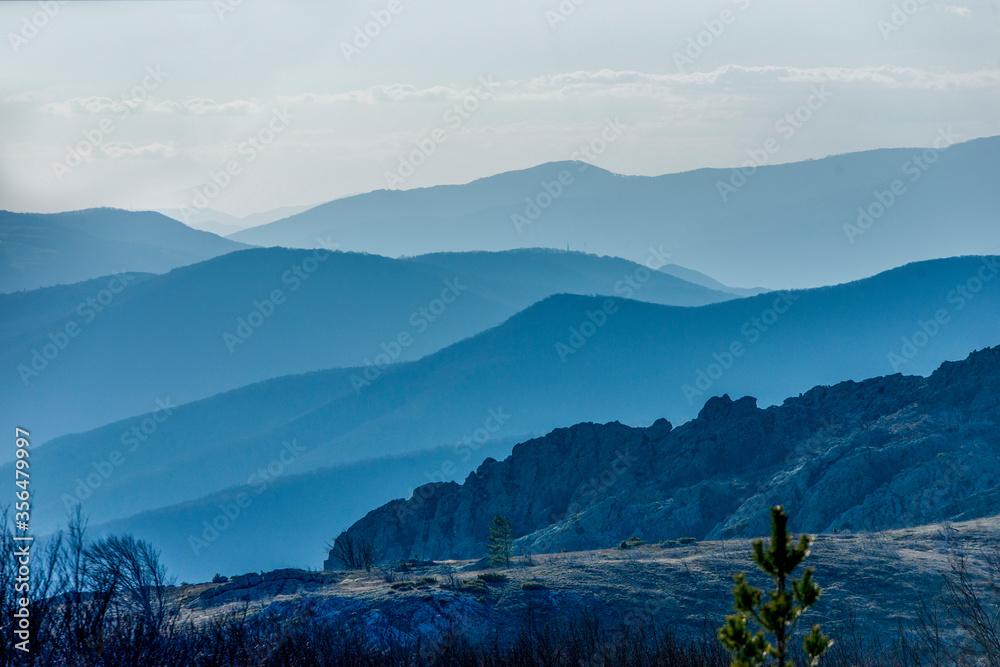 Layers of rolling hills in shades of green and blue in the distance ...