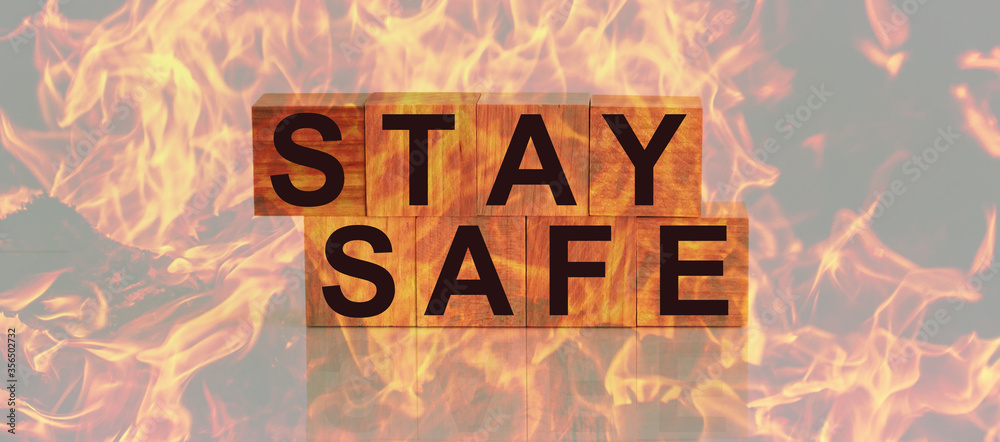 The wooden blocks say STAY SAFE. The background is a raging flame of ...