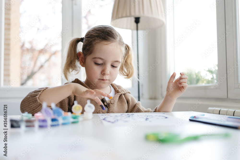 Cute child in casual outfit drawing paints with fingers while sitting ...