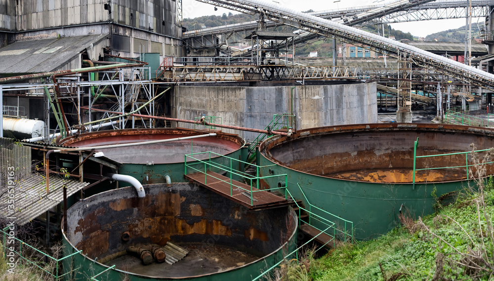 From above of huge rusted metal empty water tanks painted green ...