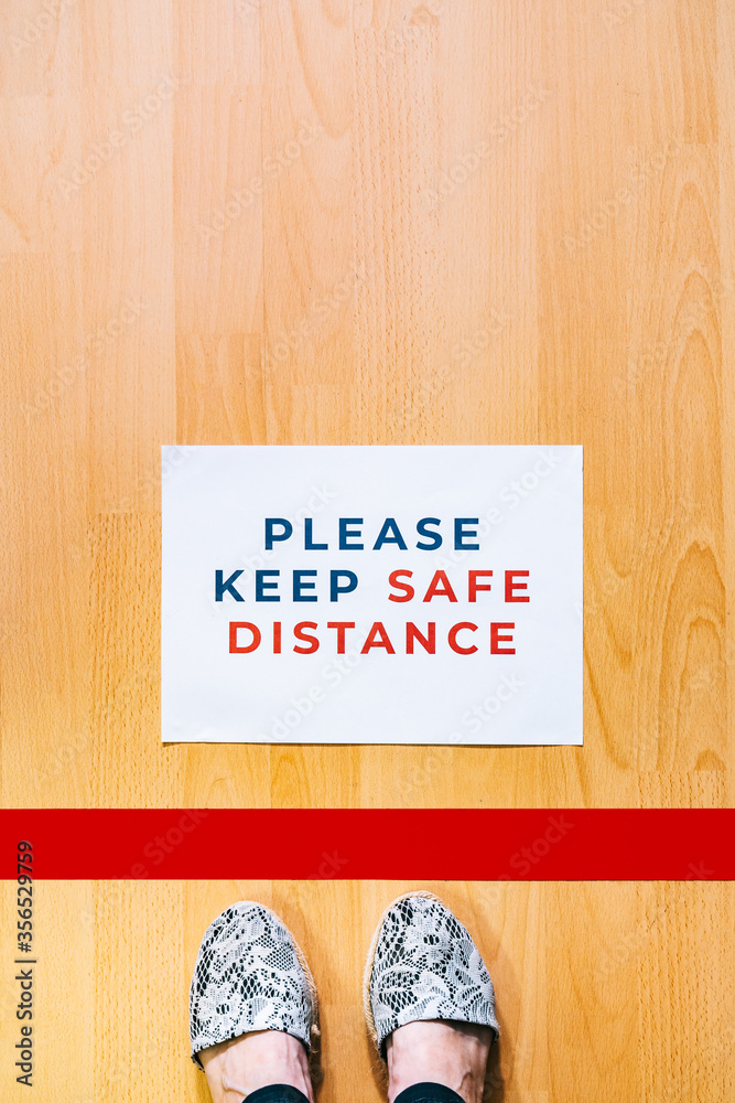 Please keep safe distance. Woman waiting behind a red line to enter a ...