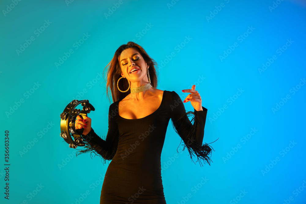 Caucasian female singer with tambourin isolated on blue studio ...