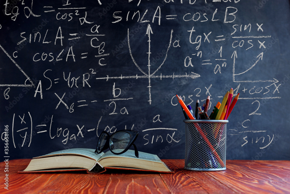 Books, pens, pencils and glasses on the table, against the background ...