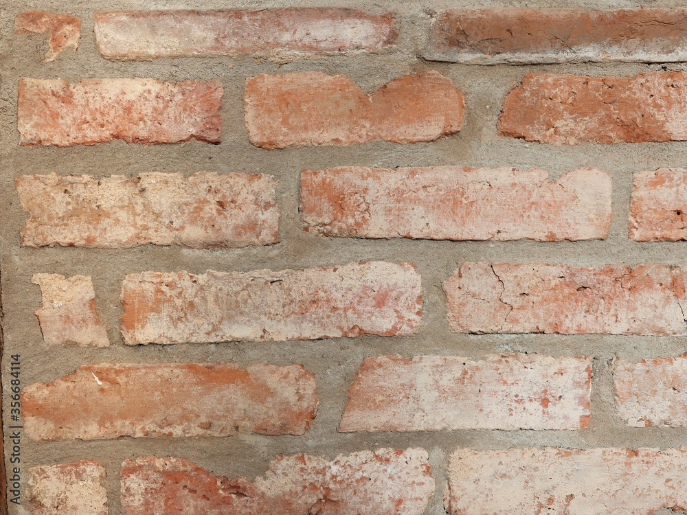 Red clay bricks on a house wall with grey wall joints in uniform color ...