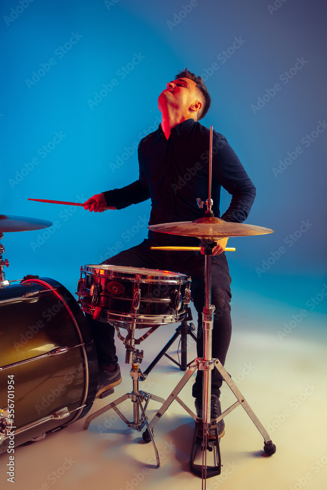 Caucasian male drummer improvising isolated on blue studio background ...