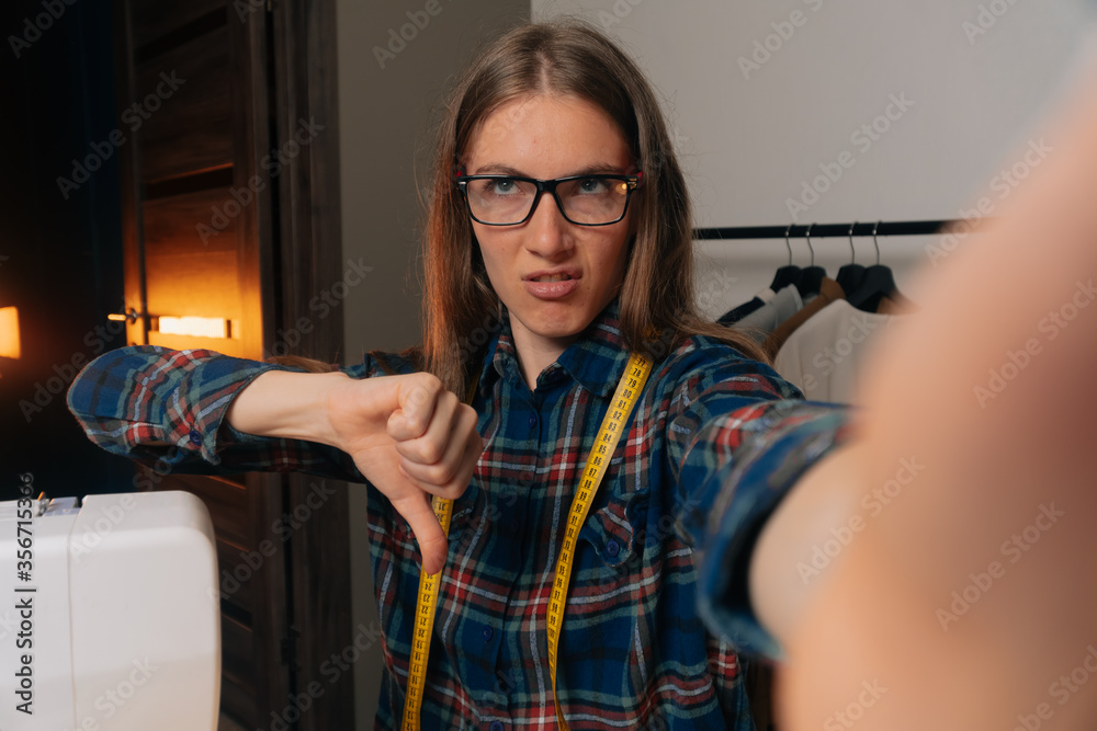 Young angry dressmaker shows all bad finger down on selfie. Girl ...