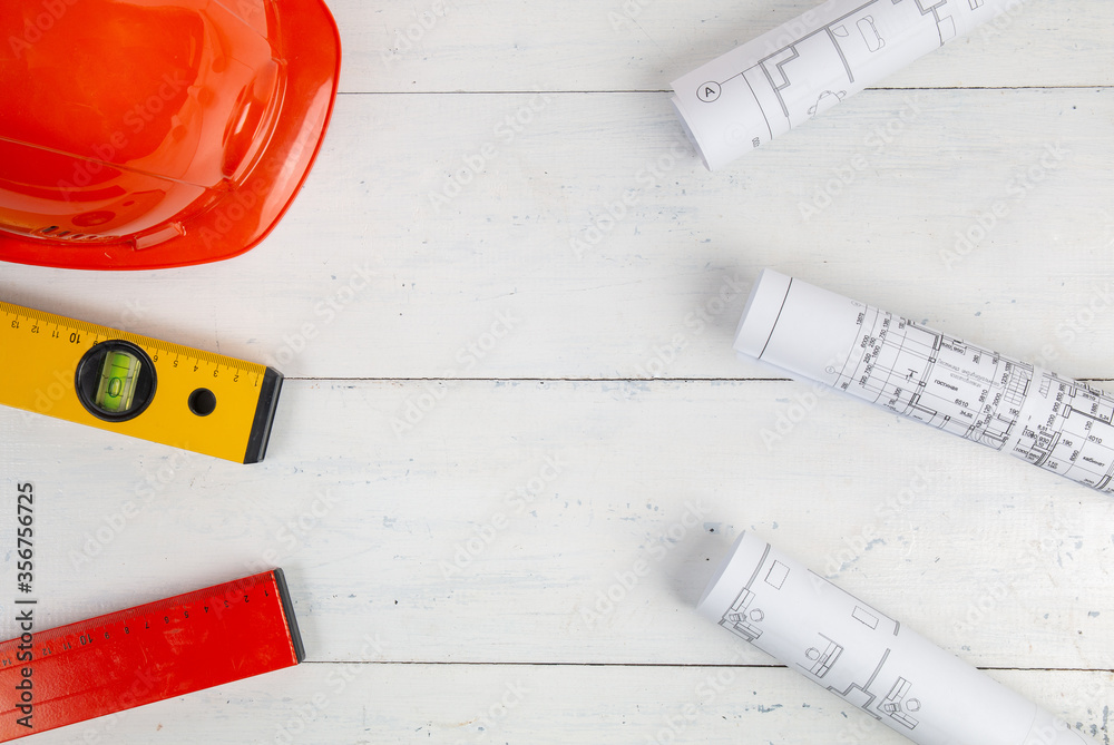 Safety helmet, paper drawings, blueprits and building level on a white ...